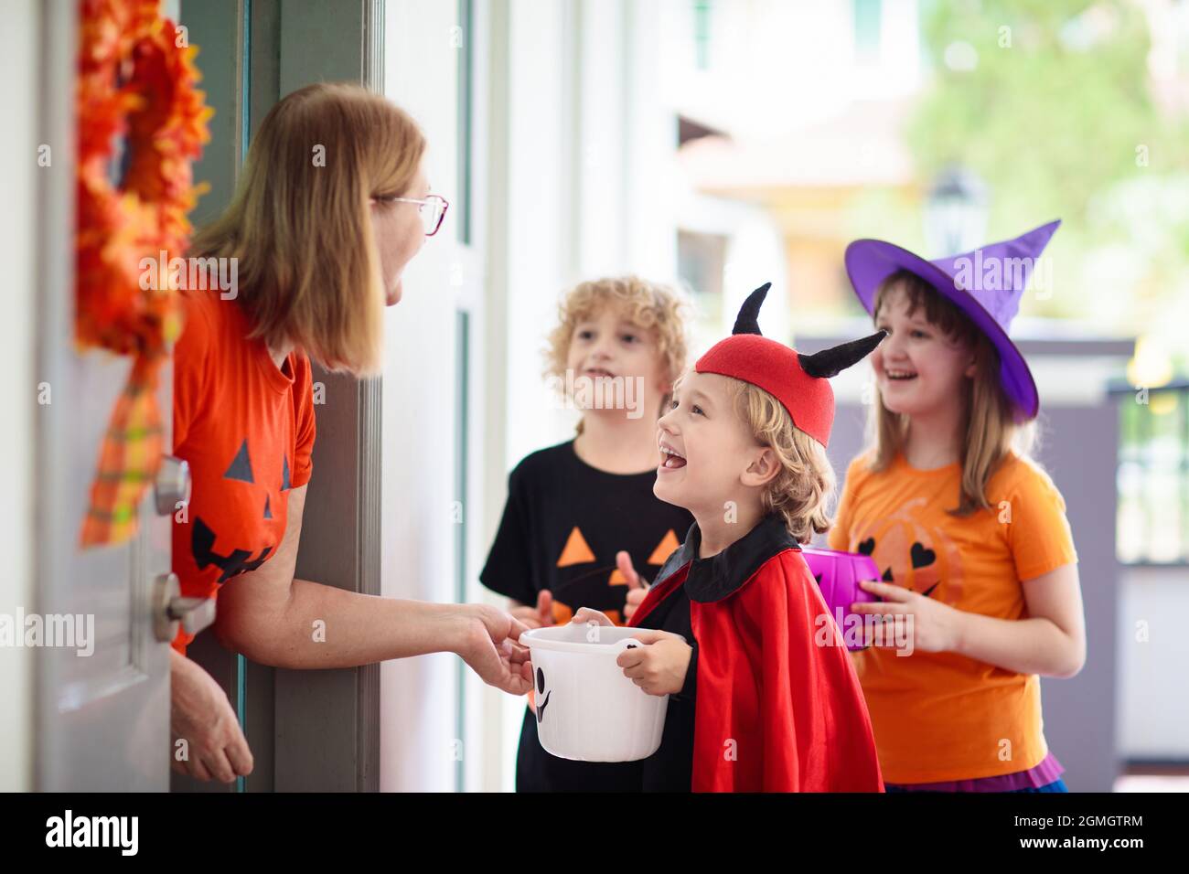 Kids trick or treat on Halloween night. Child at decorated house door ...