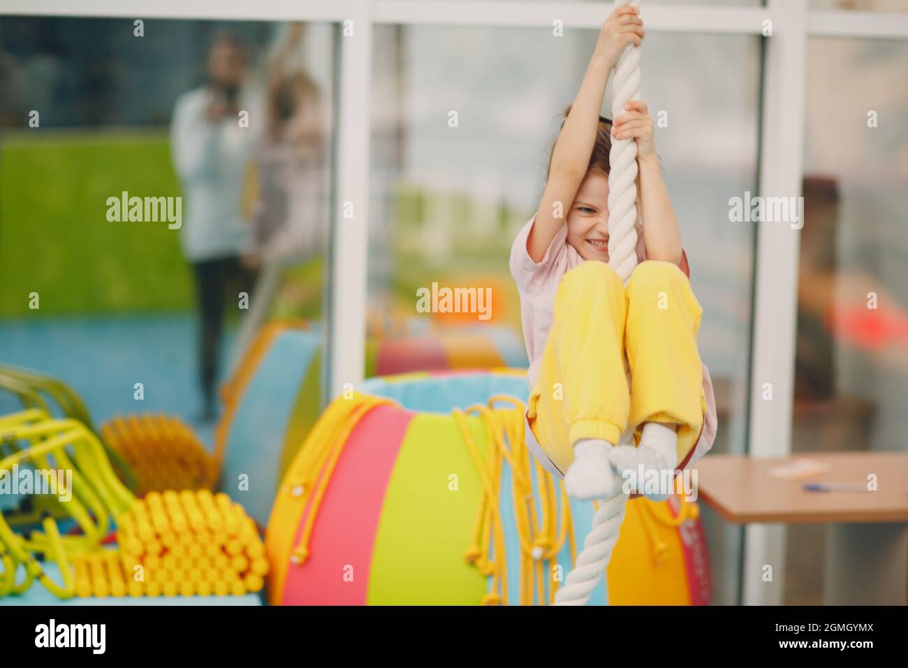 Kids doing exercises climbing tightrope in gym at kindergarten or ...
