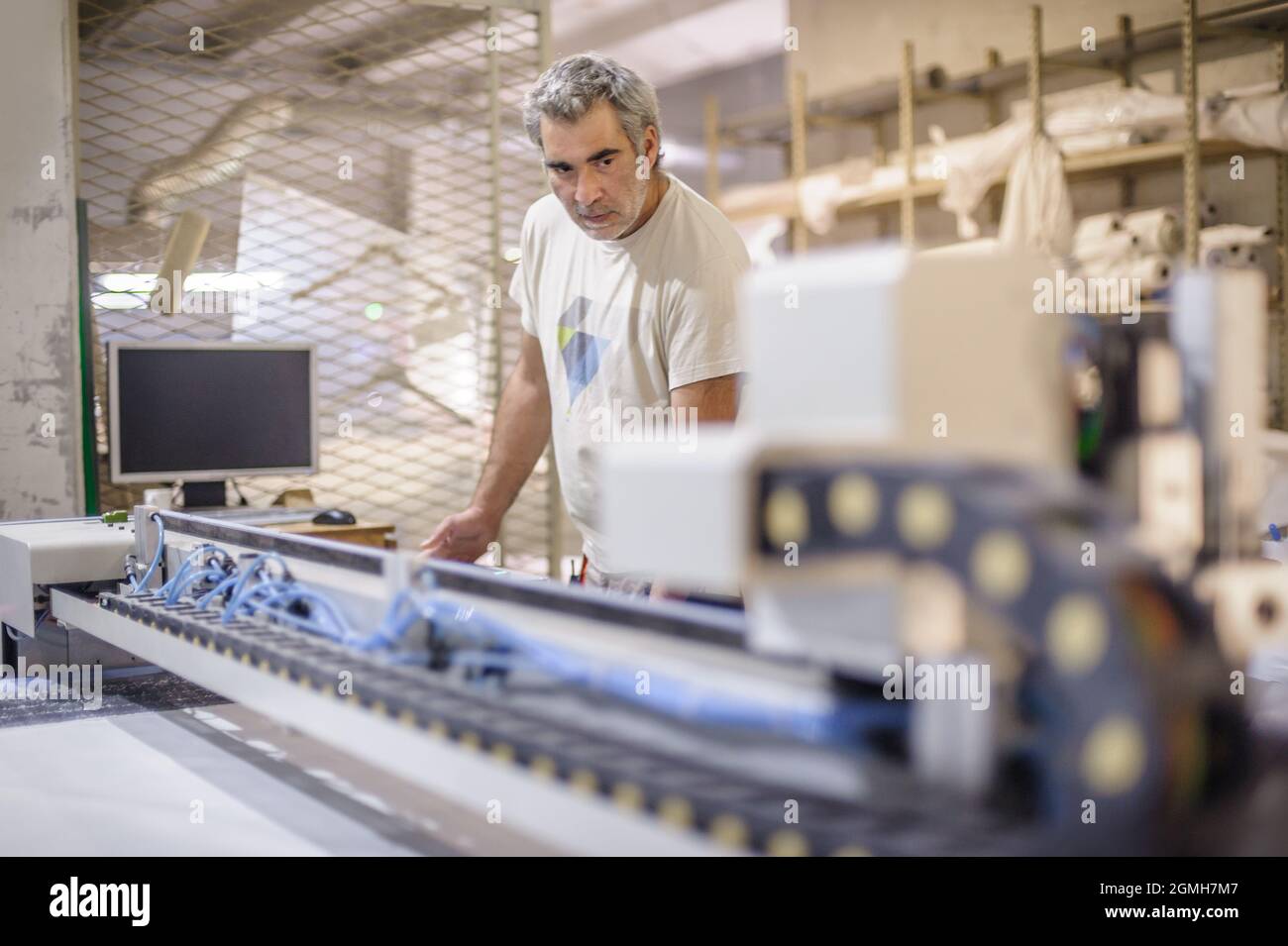 Factory worker technician works on large CNC digital cutter machine for ...
