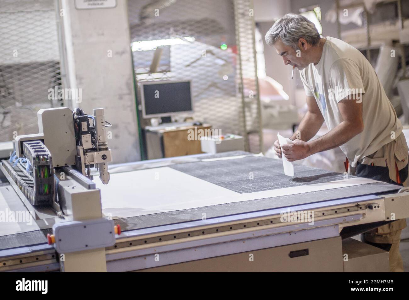 Factory worker technician works on large CNC digital cutter machine for ...