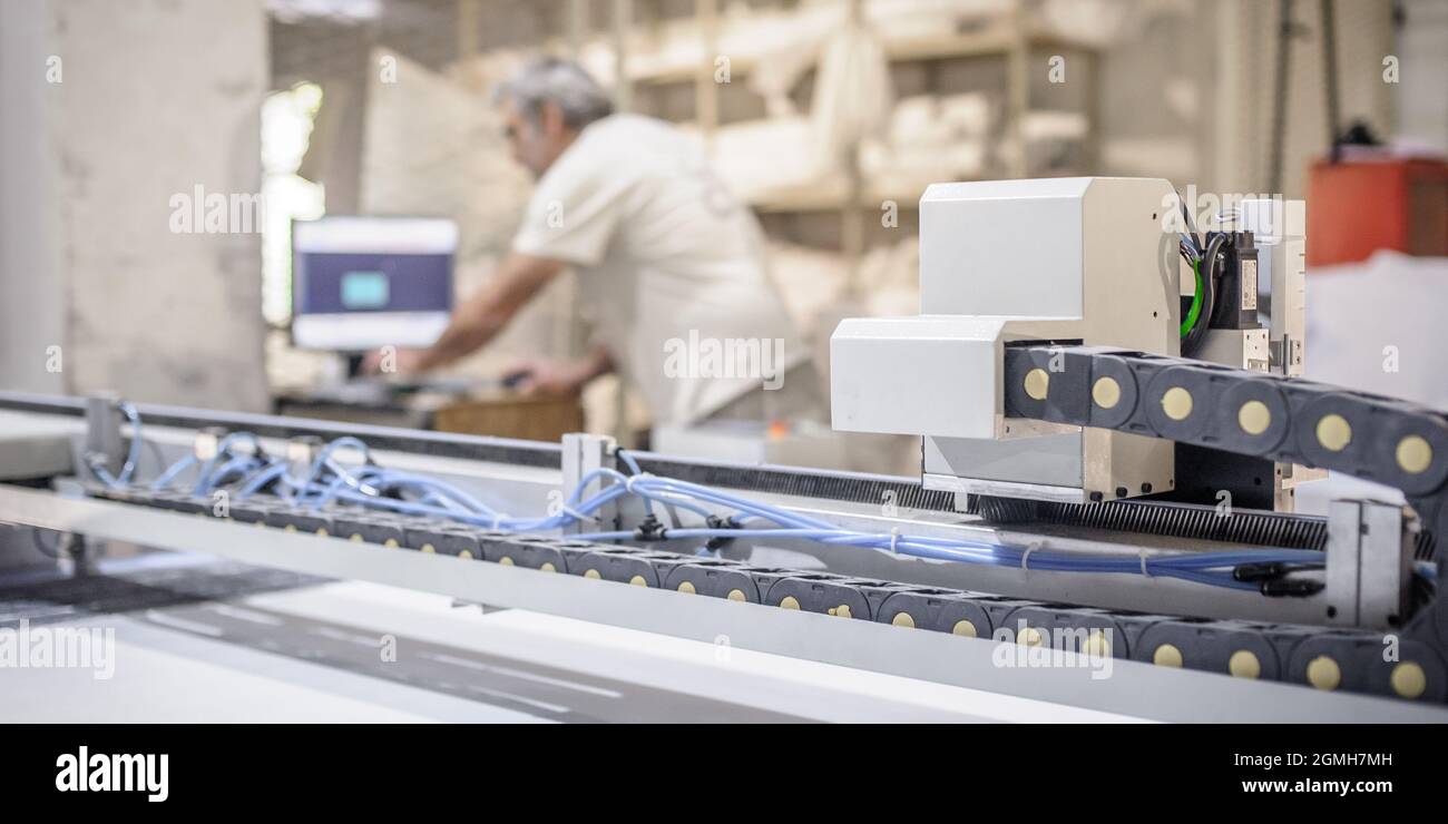 Factory worker technician works on large CNC digital cutter machine for ...