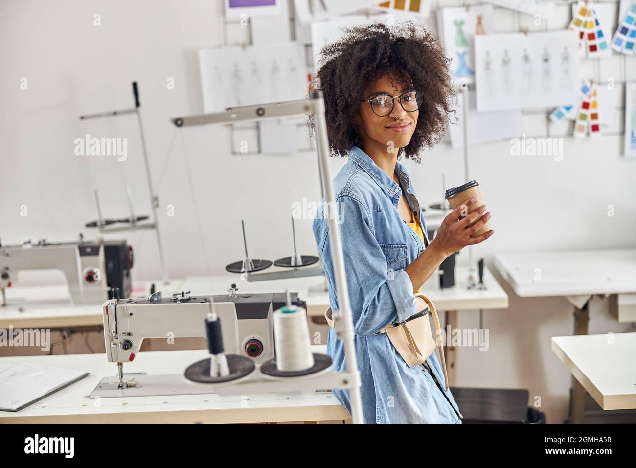 African-American woman dressmaker with cup and belt bag leans onto ...