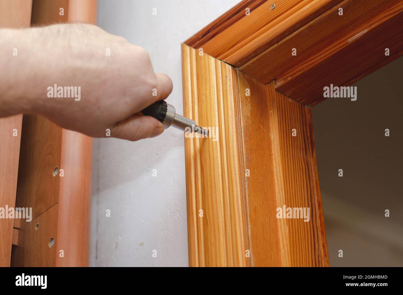 A man installs a wooden door trim. The hand screwdriver screws i Stock ...