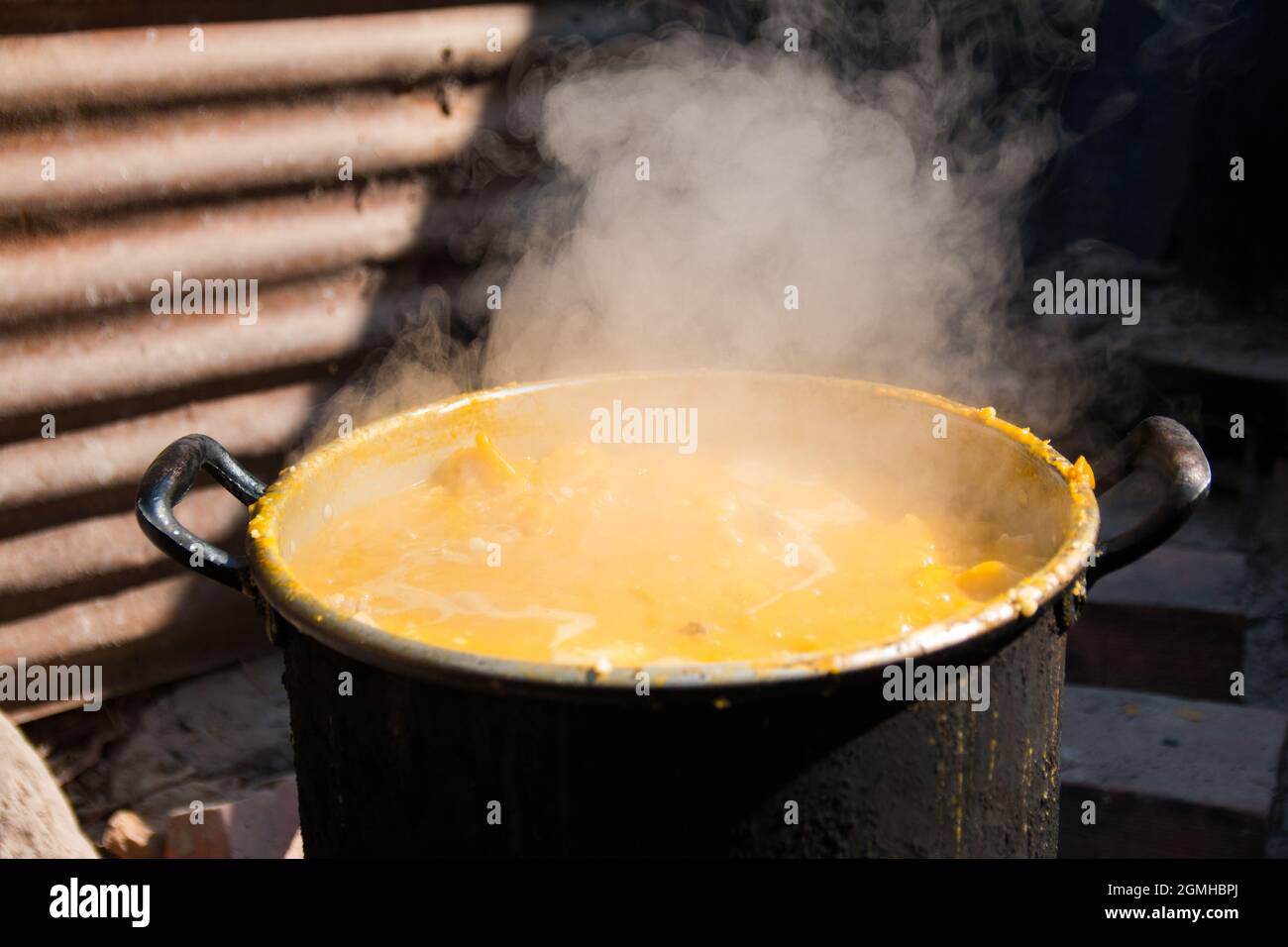 A yellow soup boiling on fire outdoors Stock Photo - Alamy