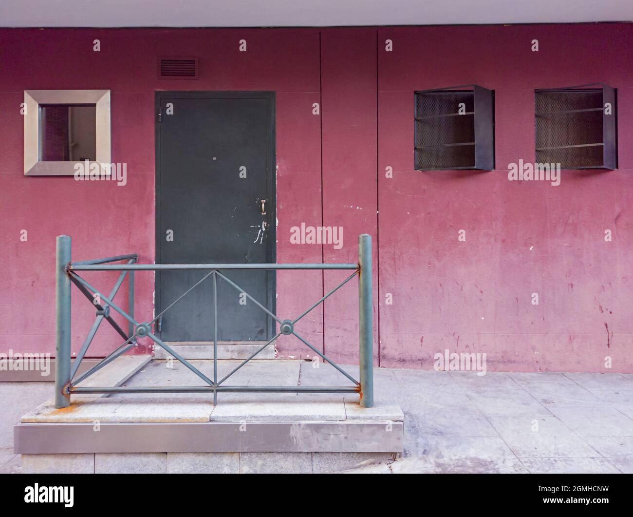 Back of a building, with small, square windows and a metal door in a ...