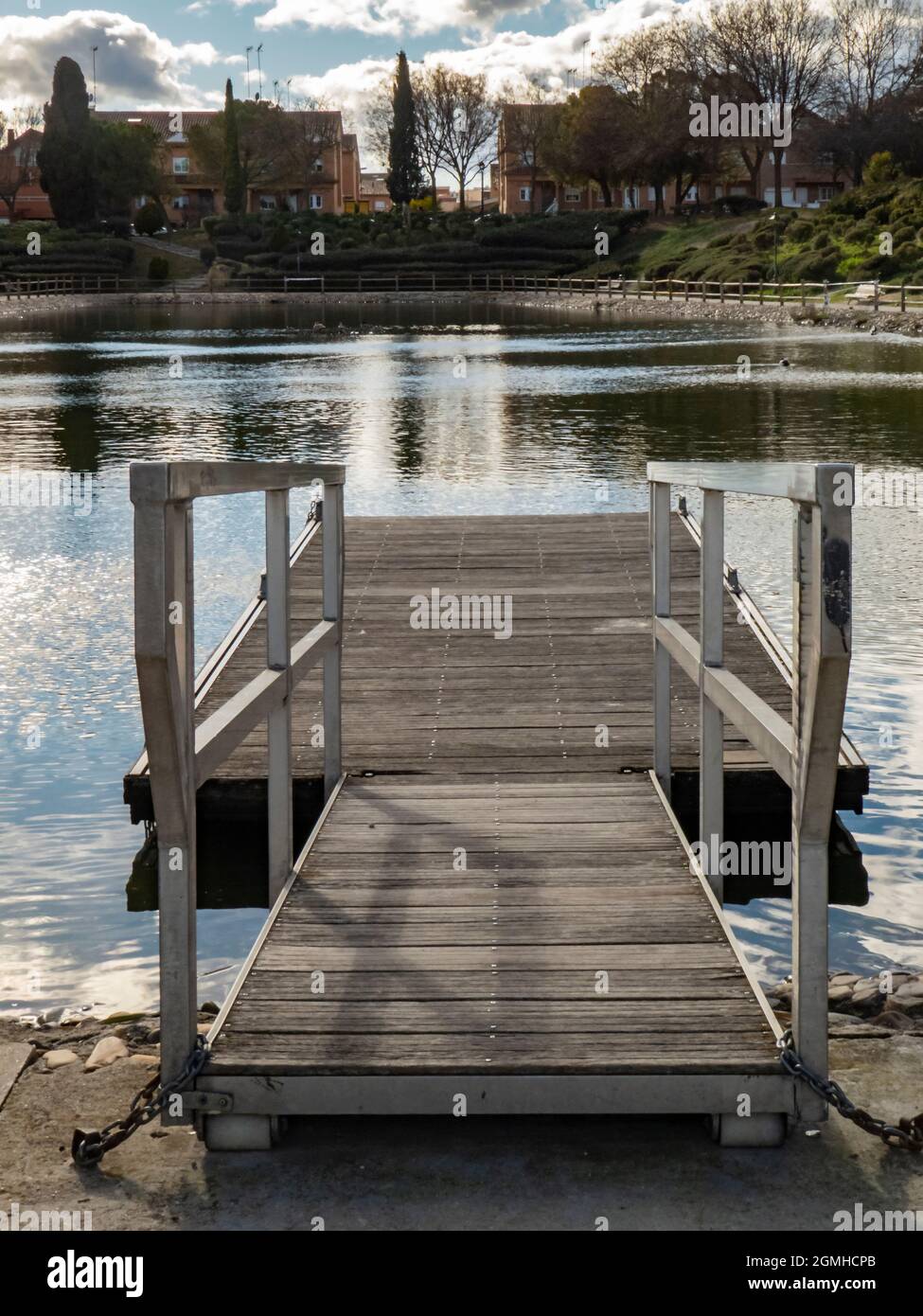 Floating wooden platform on a pond in a city park with houses in the ...