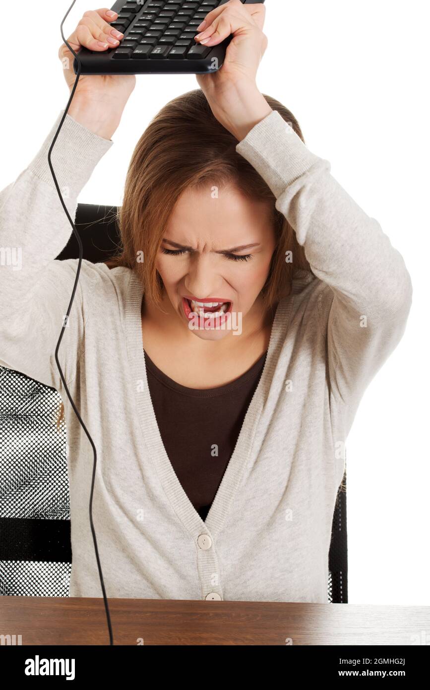 A blonde Caucasian woman throwing her keyboard with an angry face ...