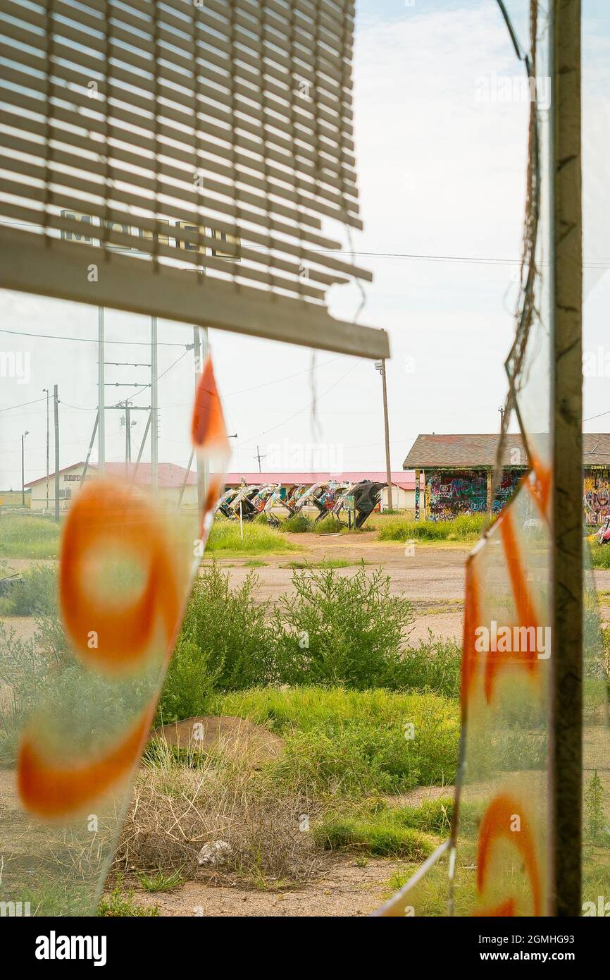 view through broken glass window of abandoned motel painted Volkswagen ...