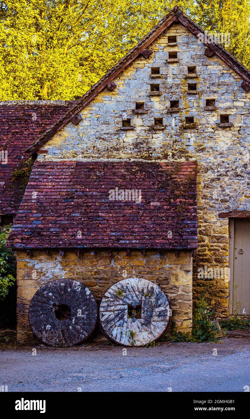 Two old mill stones propped against an old barn Stock Photo - Alamy