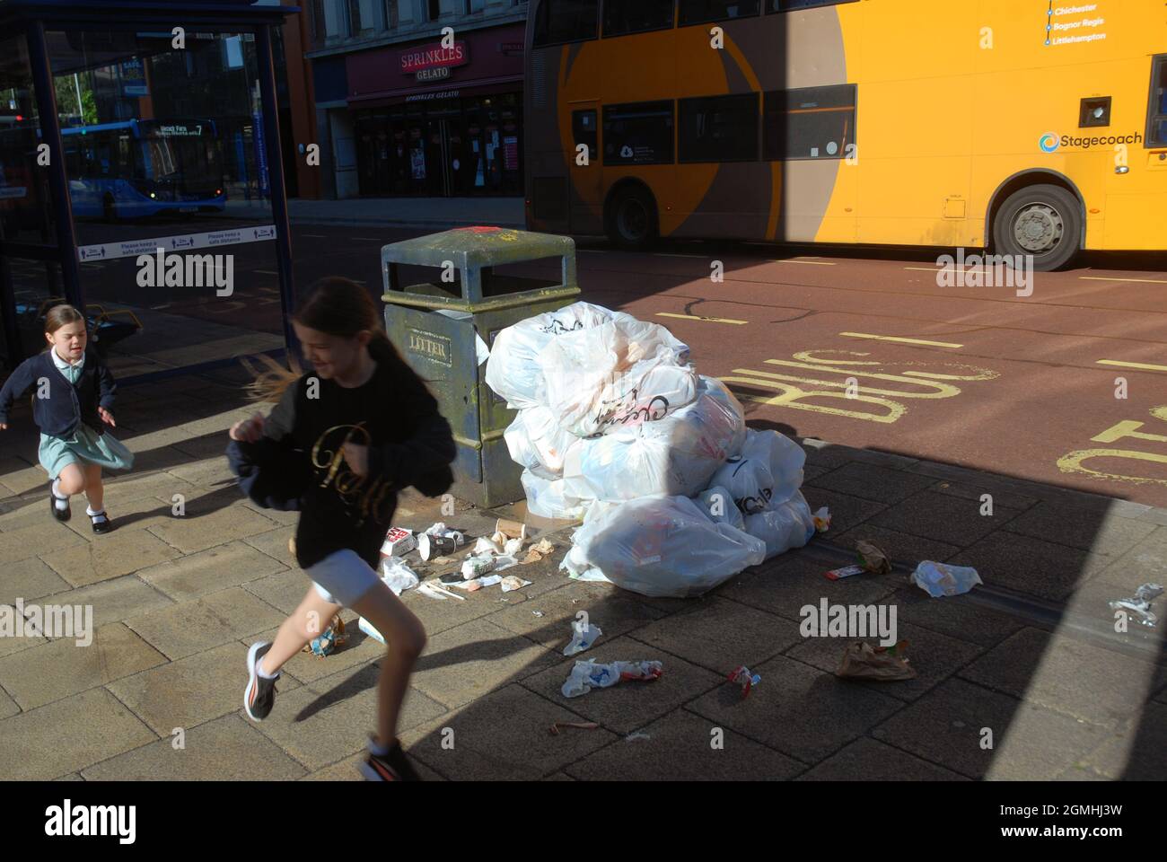 Two girls running past an overflowing rubbish bin, Portsmouth ...