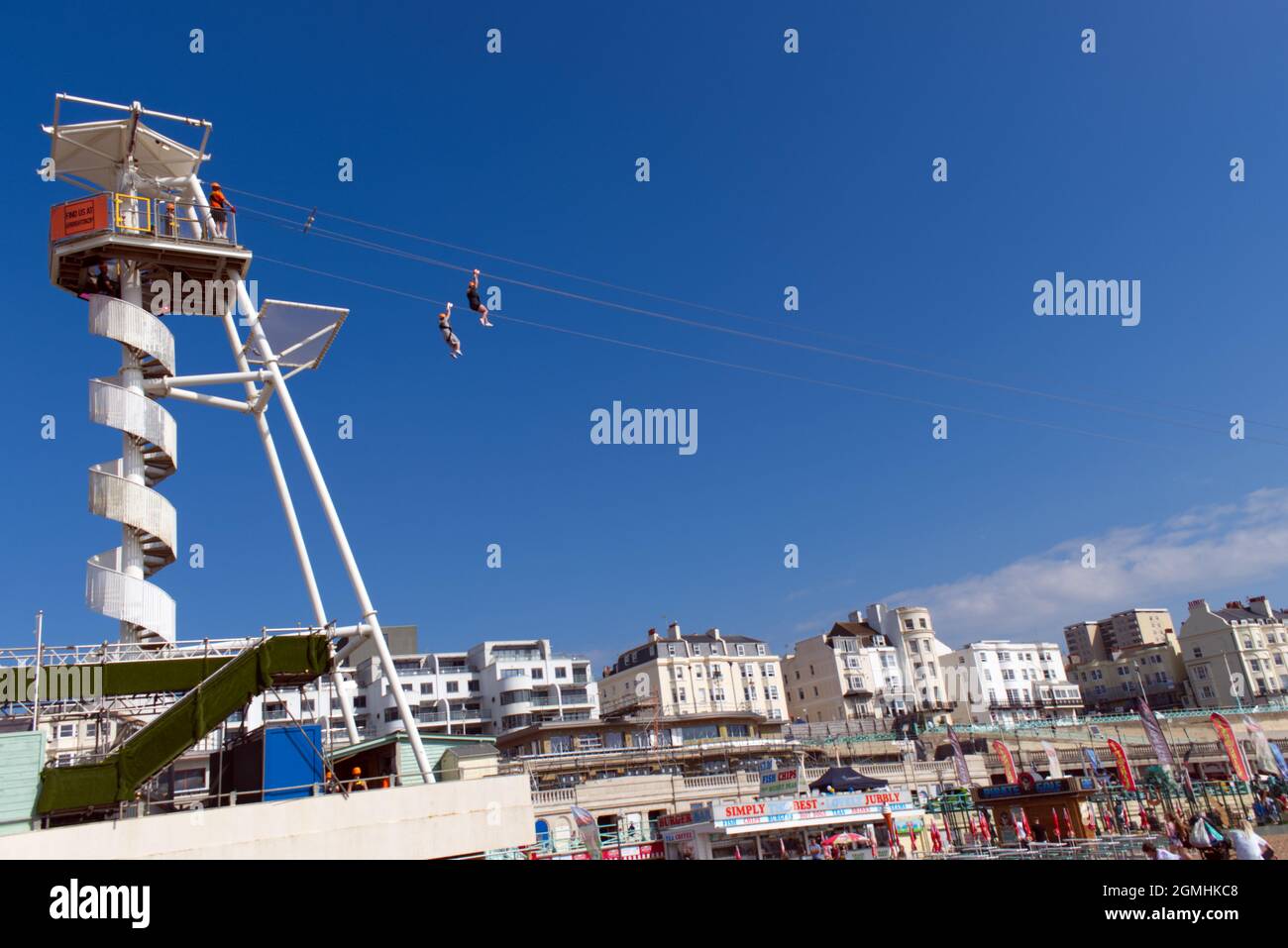 Two people riding the Zip Wire on Brighton beach on a sunny and warm ...
