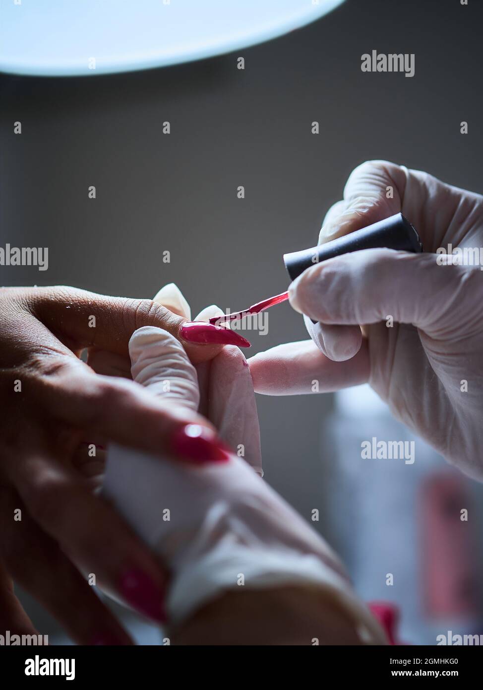 A vertical shotof a nail master painting the customer's nails bright ...