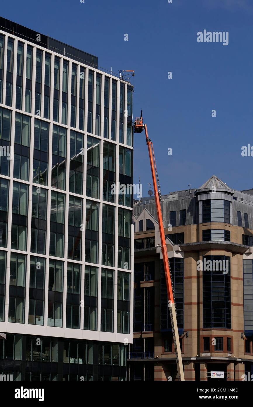 a worker at the top of an extending platform applies finishing pieces ...