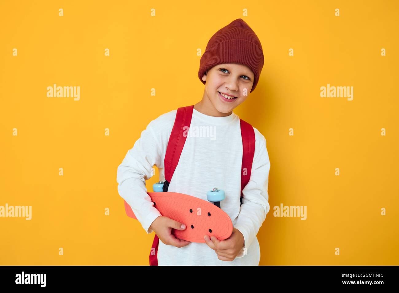 happy schoolboy in a red hat skateboard in his hands yellow color ...