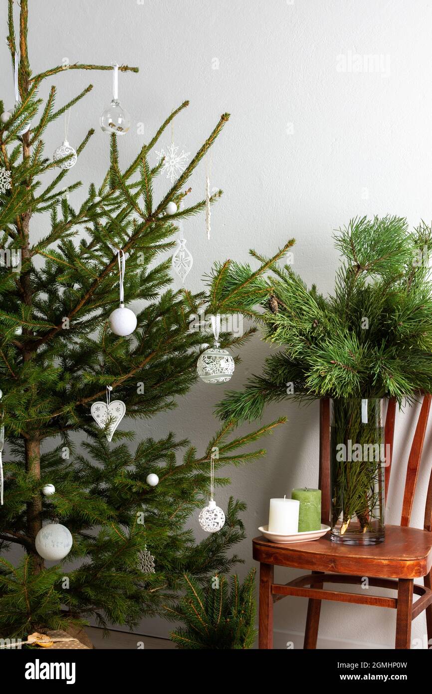 Christmas tree with white toys, old chair with a vase with pine ...
