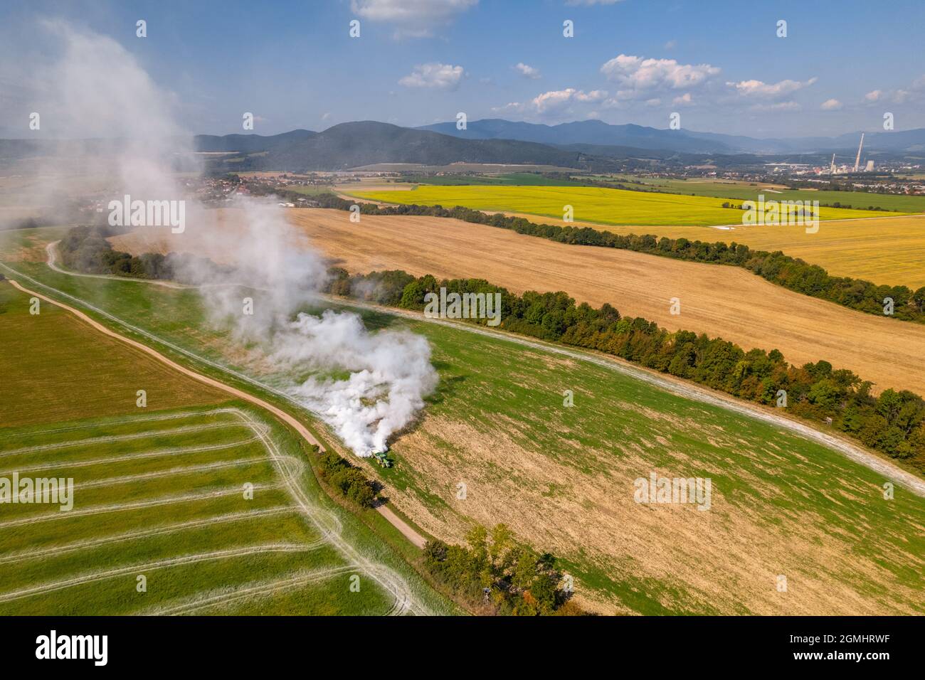 Aerial view of a tractor spreading lime on agricultural fields to ...