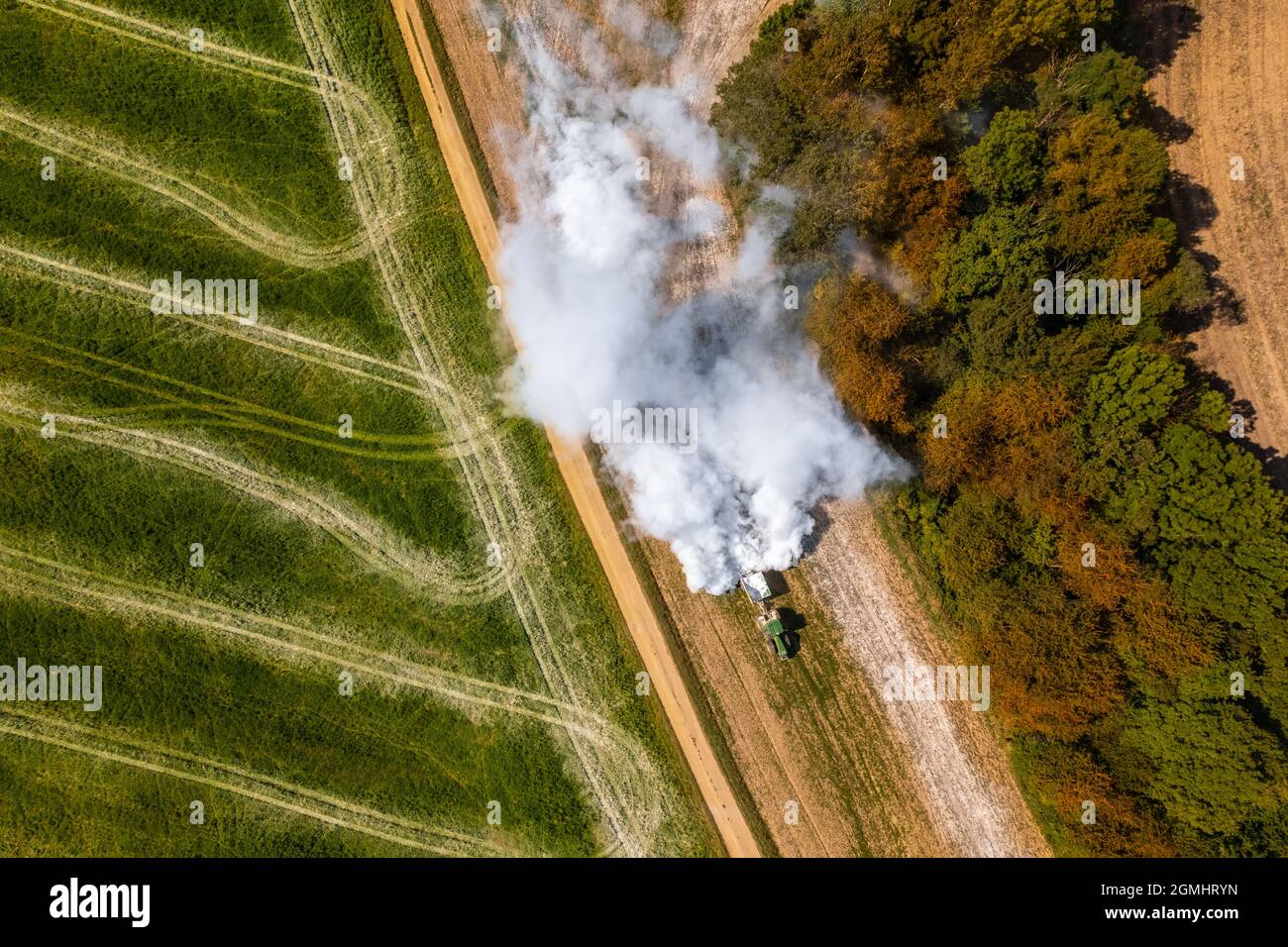 Aerial view of a tractor spreading lime on agricultural fields to ...