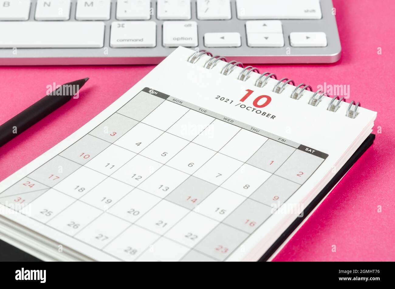 October 2021 desk calendar with pen and keyboard computer on pink ...