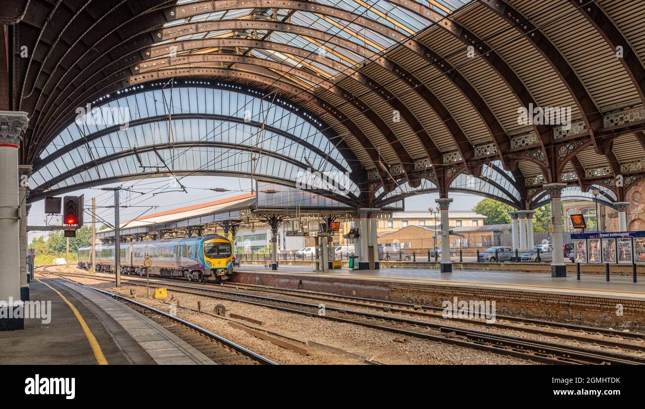 Railway station platforms with a train pulling in. An iron and glass ...