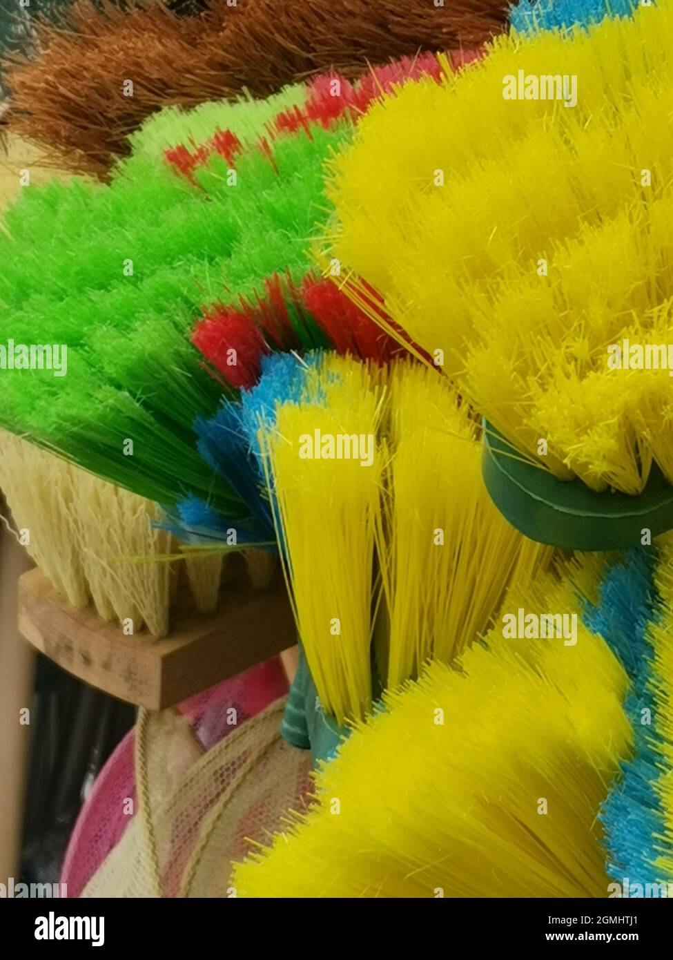 Full frame image of assorted nylon and bristle brooms in bright colours ...