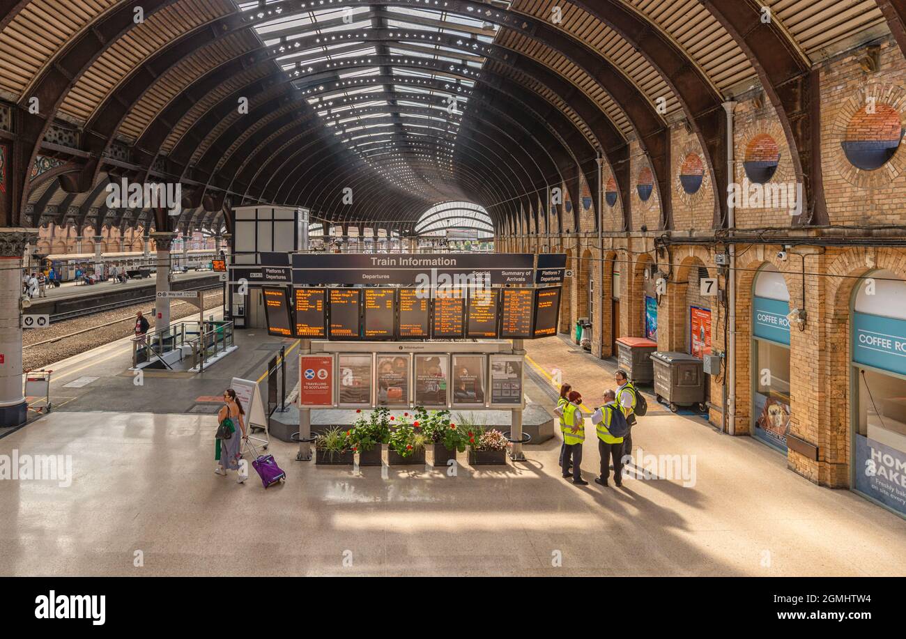 A station concourse with an electronic notice board. An elaborate 19th ...