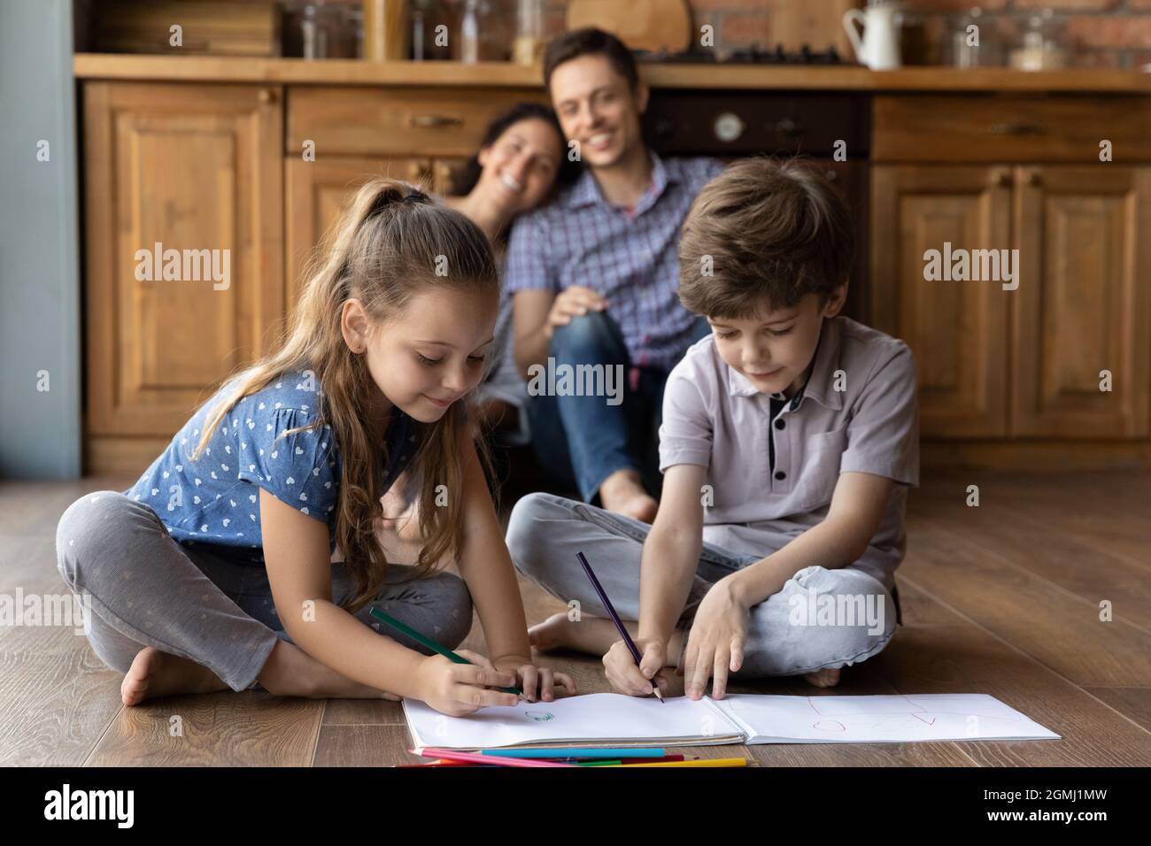 Happy children drawing while parents resting on floor Stock Photo - Alamy