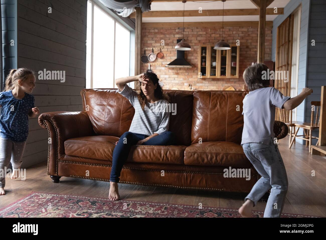 Stressed young mother feeling exhausted of hyperactive small children ...