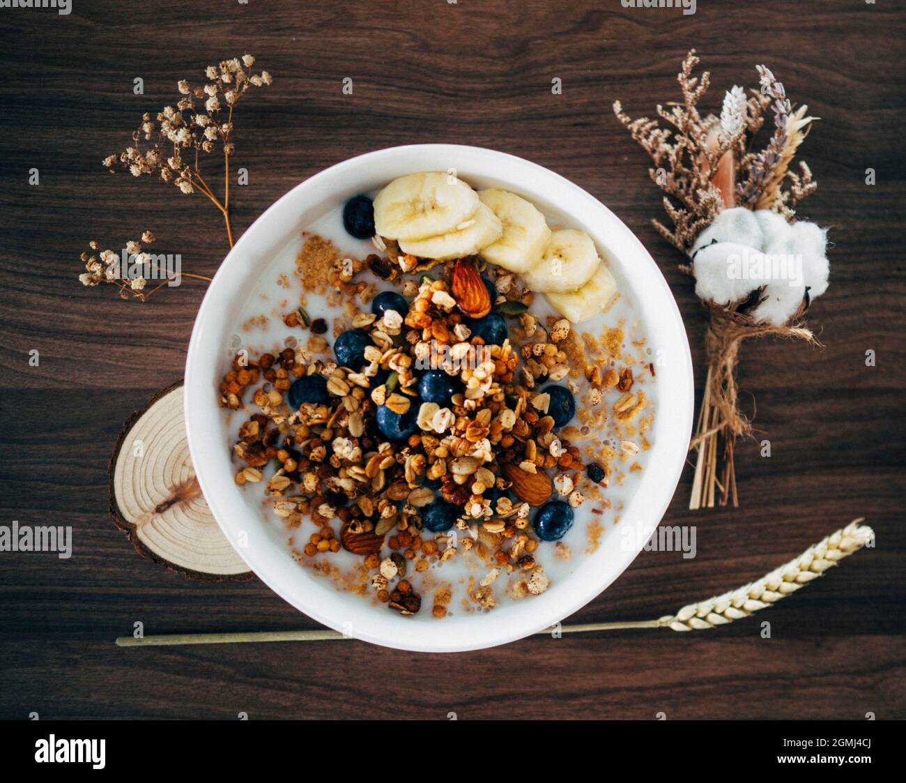 Flatlay cereal in milk granola banana blueberries cotton flowers Stock ...