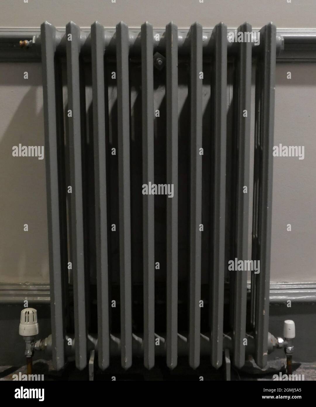 Dark grey old-fashioned cast iron radiator in period setting with dado ...