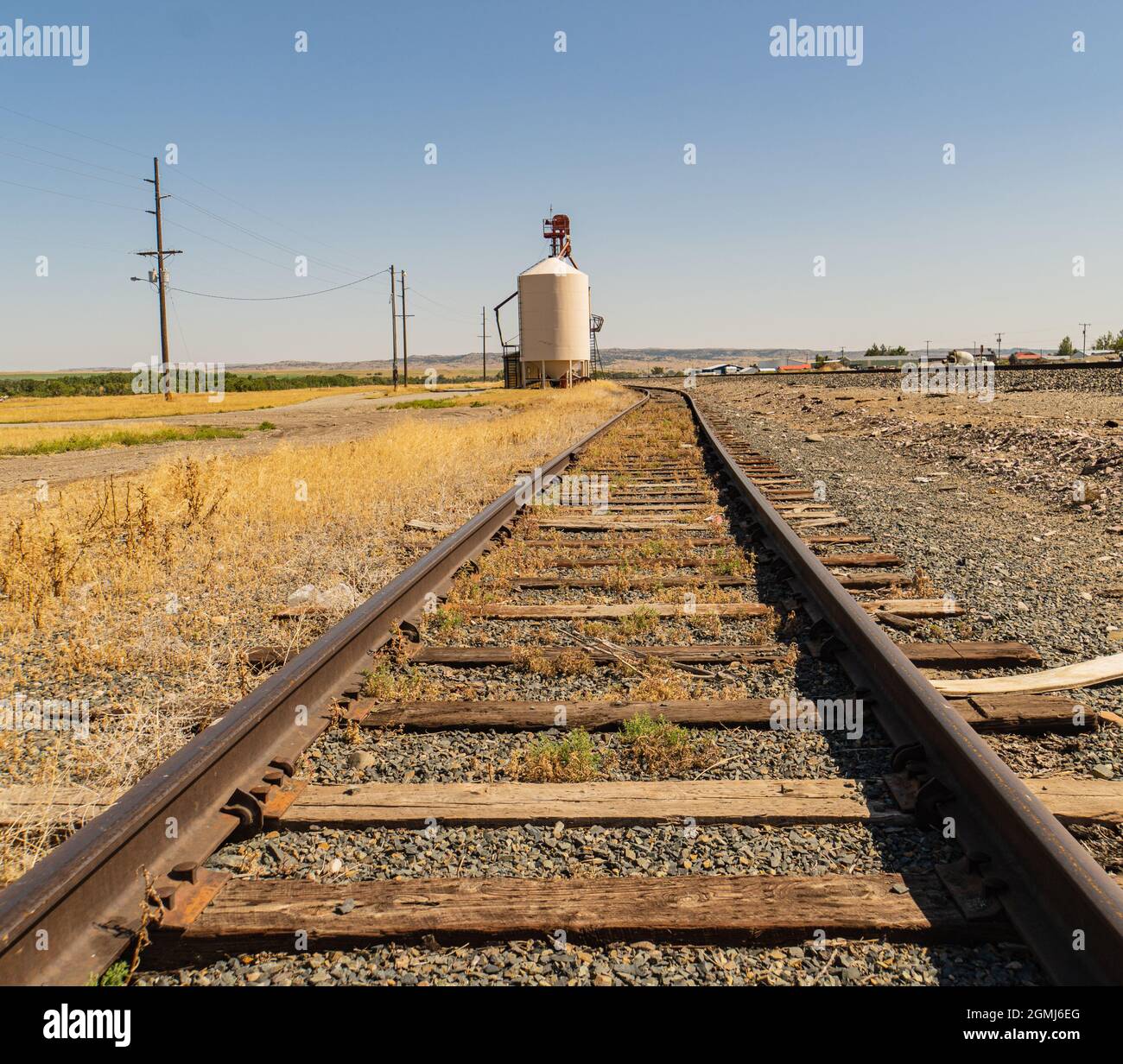 railroad tracts curve off to the left near a granary on the flat plains ...