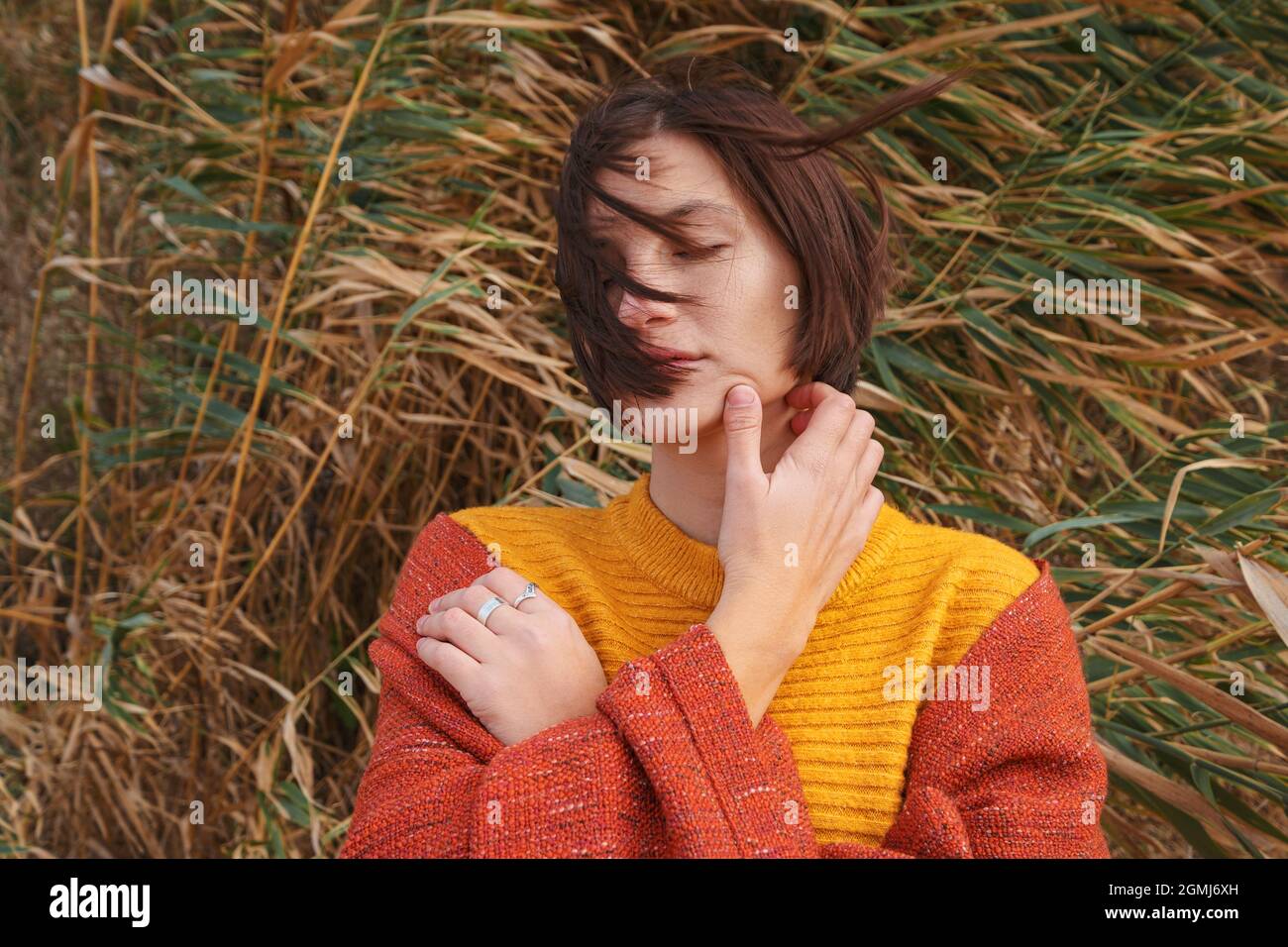 Attractive young woman standing on a windy cold beach wrapped in warm ...