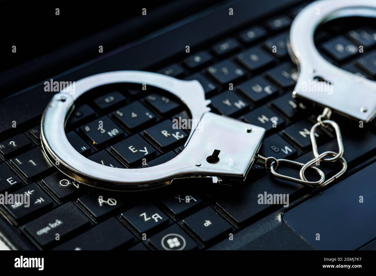 Silvery handcuffs lie on the laptop keyboard. computer crimes. High ...