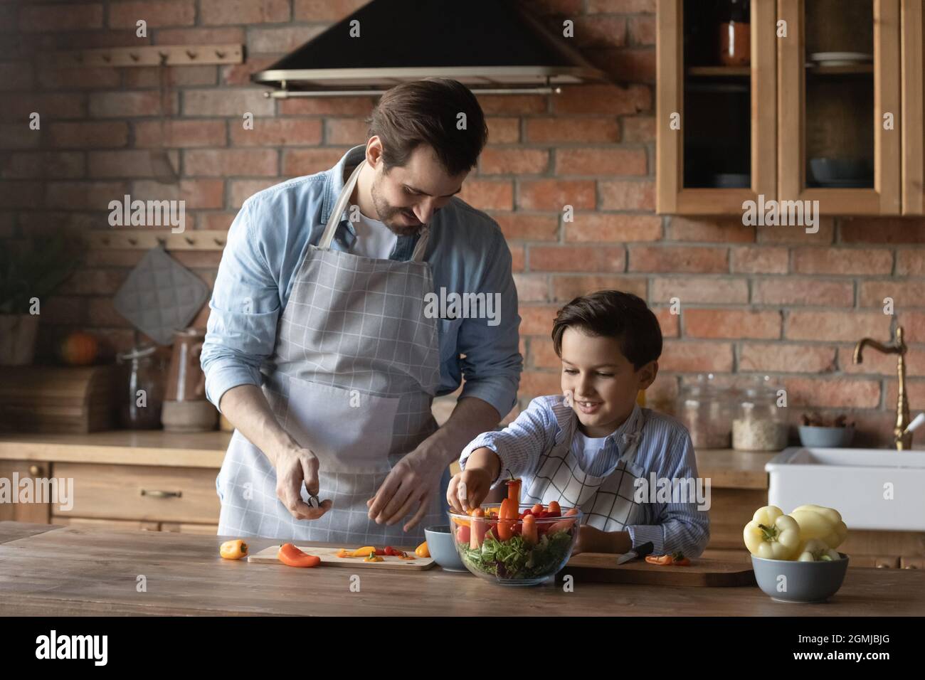 Happy father and little son wearing aprons cooking together Stock Photo ...