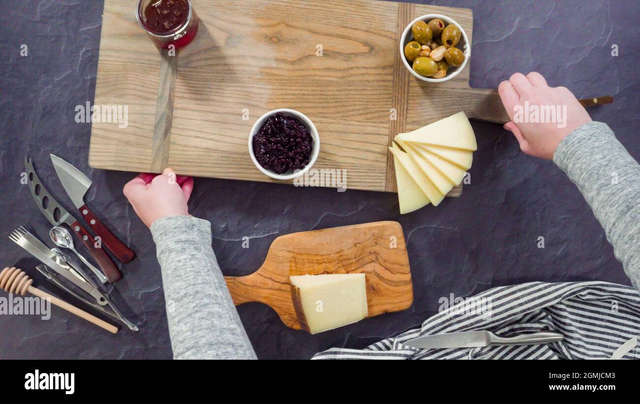 Flat lay. Arranging gourmet cheese, crakers, and fruits on a board for ...