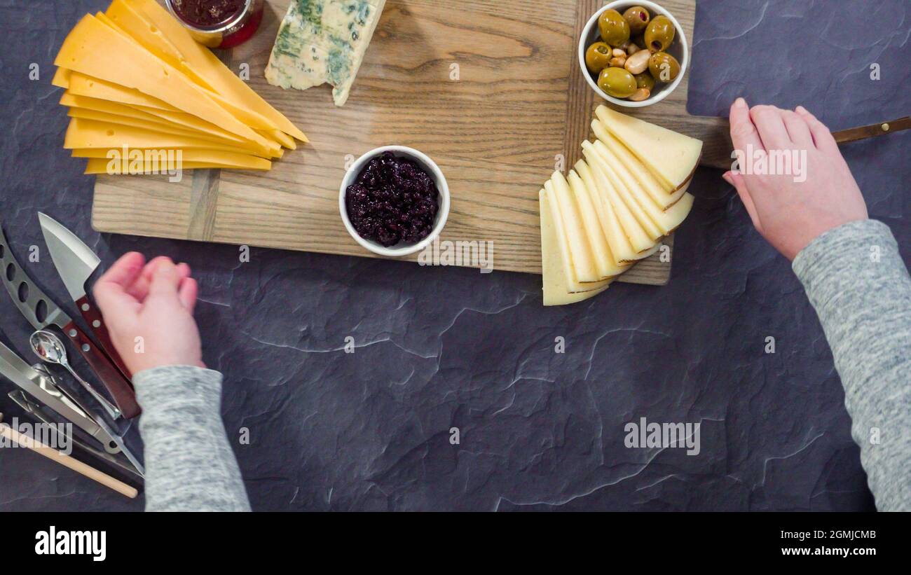 Flat lay. Arranging gourmet cheese, crakers, and fruits on a board for ...