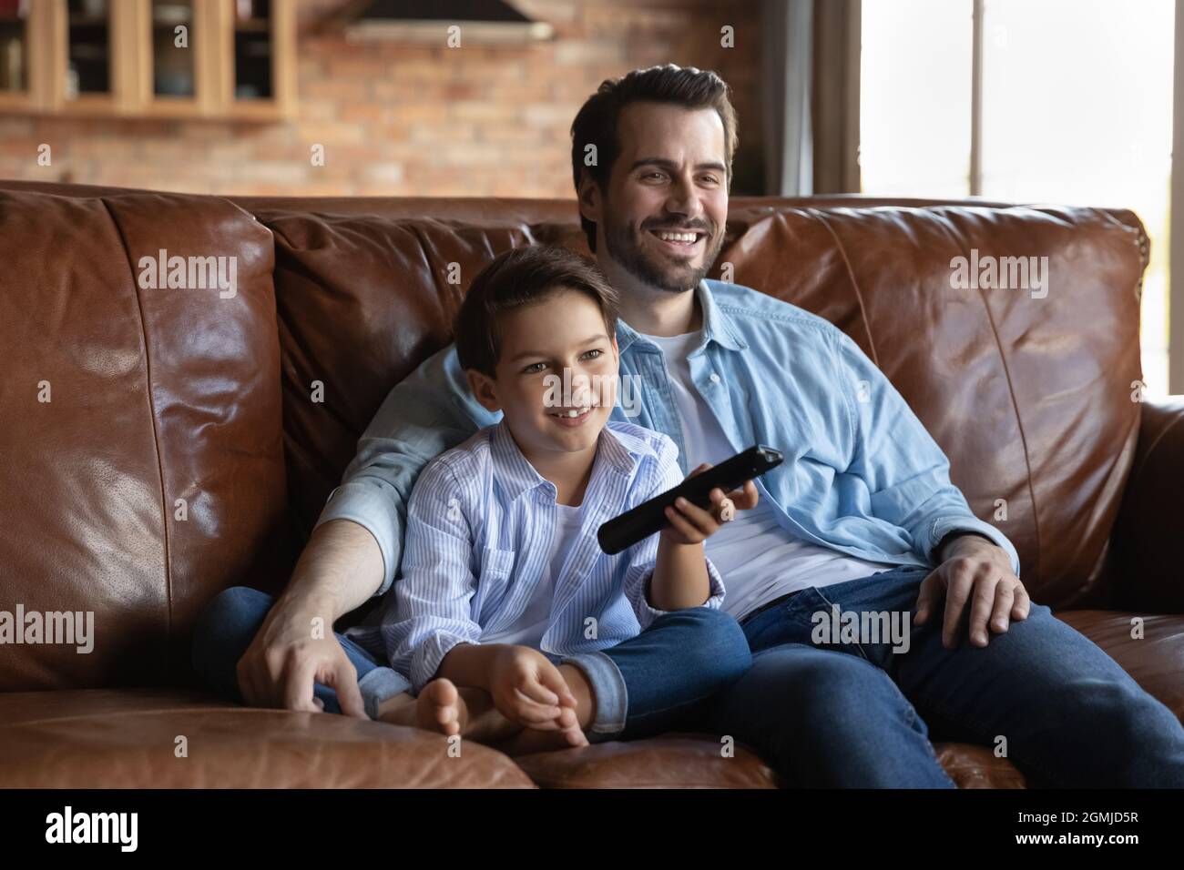 Happy father with little son watching tv, sitting on couch Stock Photo ...