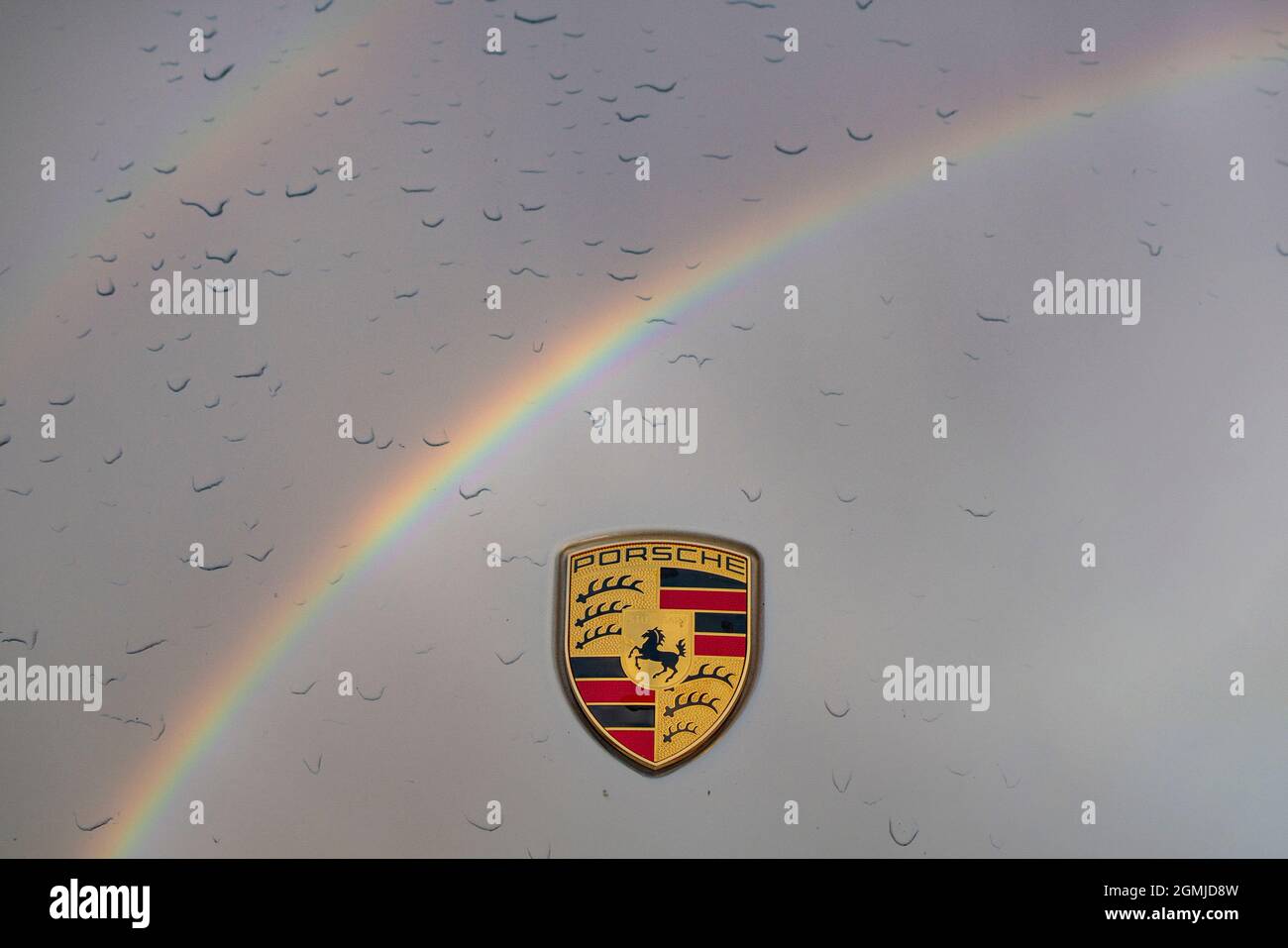 Porsche badge on the bonnet of 911 with droplets of rain water and a ...