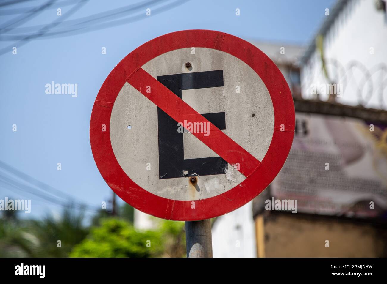 A closeup shot of a round red street sign with the letter E for no ...
