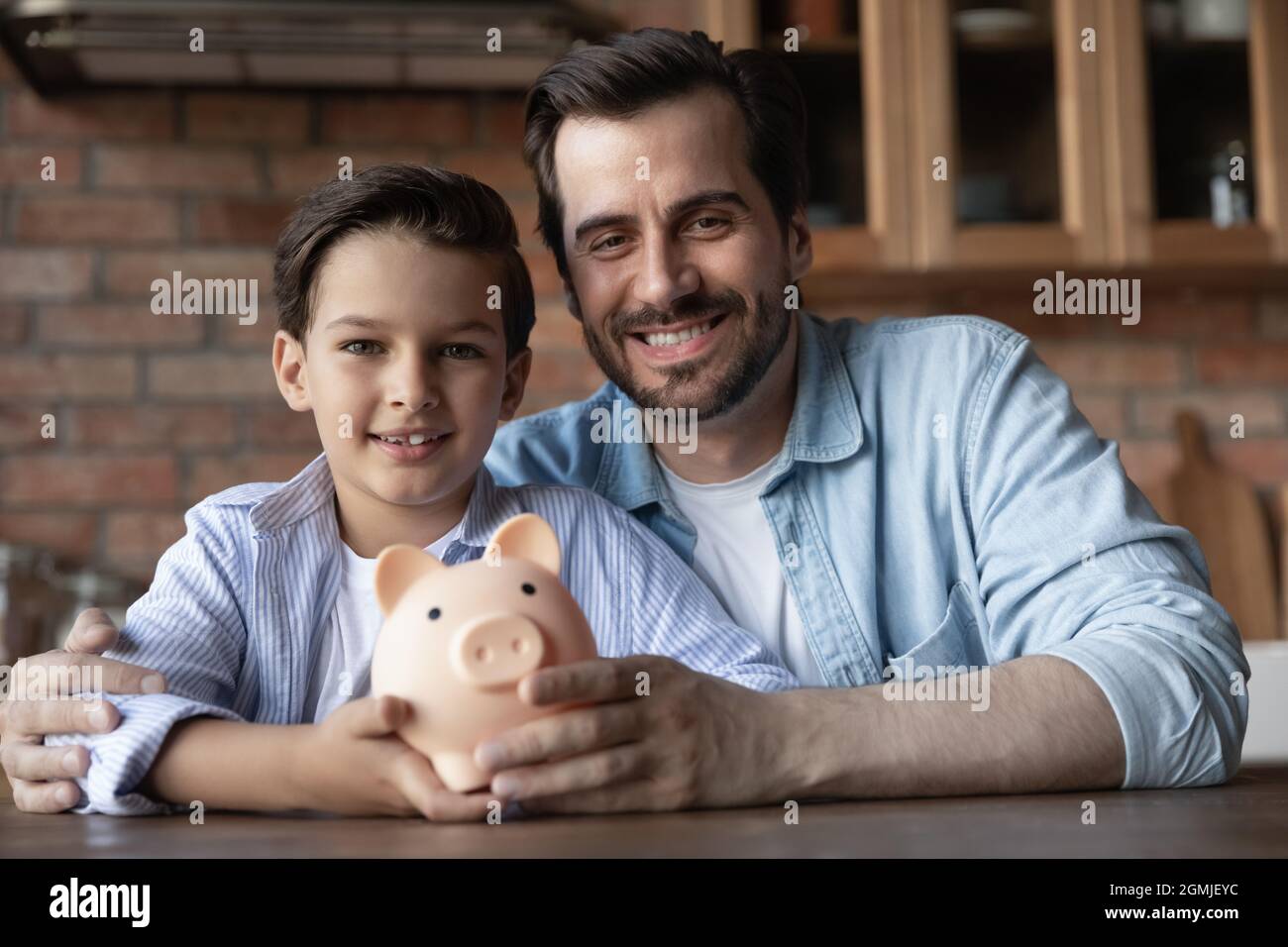 Head shot portrait smiling father and son with piggy bank Stock Photo ...