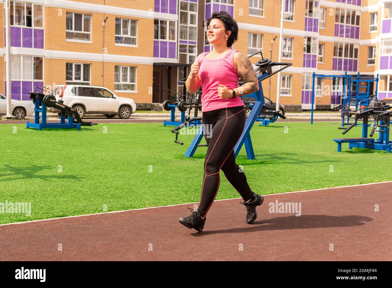 woman jogging on a sports ground in the courtyard of a city house ...
