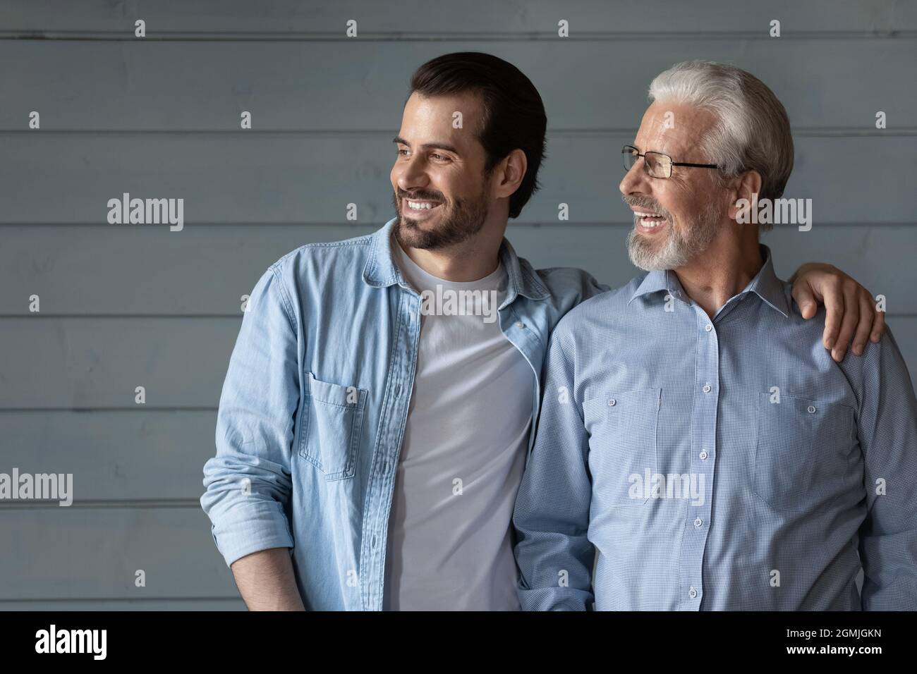 Happy two generations of men hugging, looking in distance Stock Photo ...