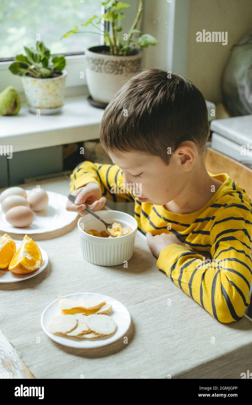 boy eats breakfast in the morning with cereals with milk. Morning ...