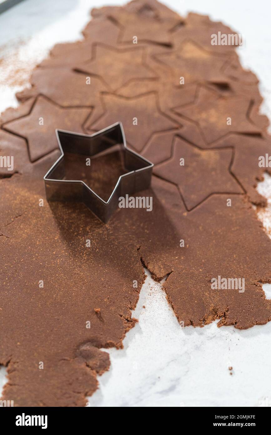 Cutting star-shaped chocolate graham crackers from the dough with a ...