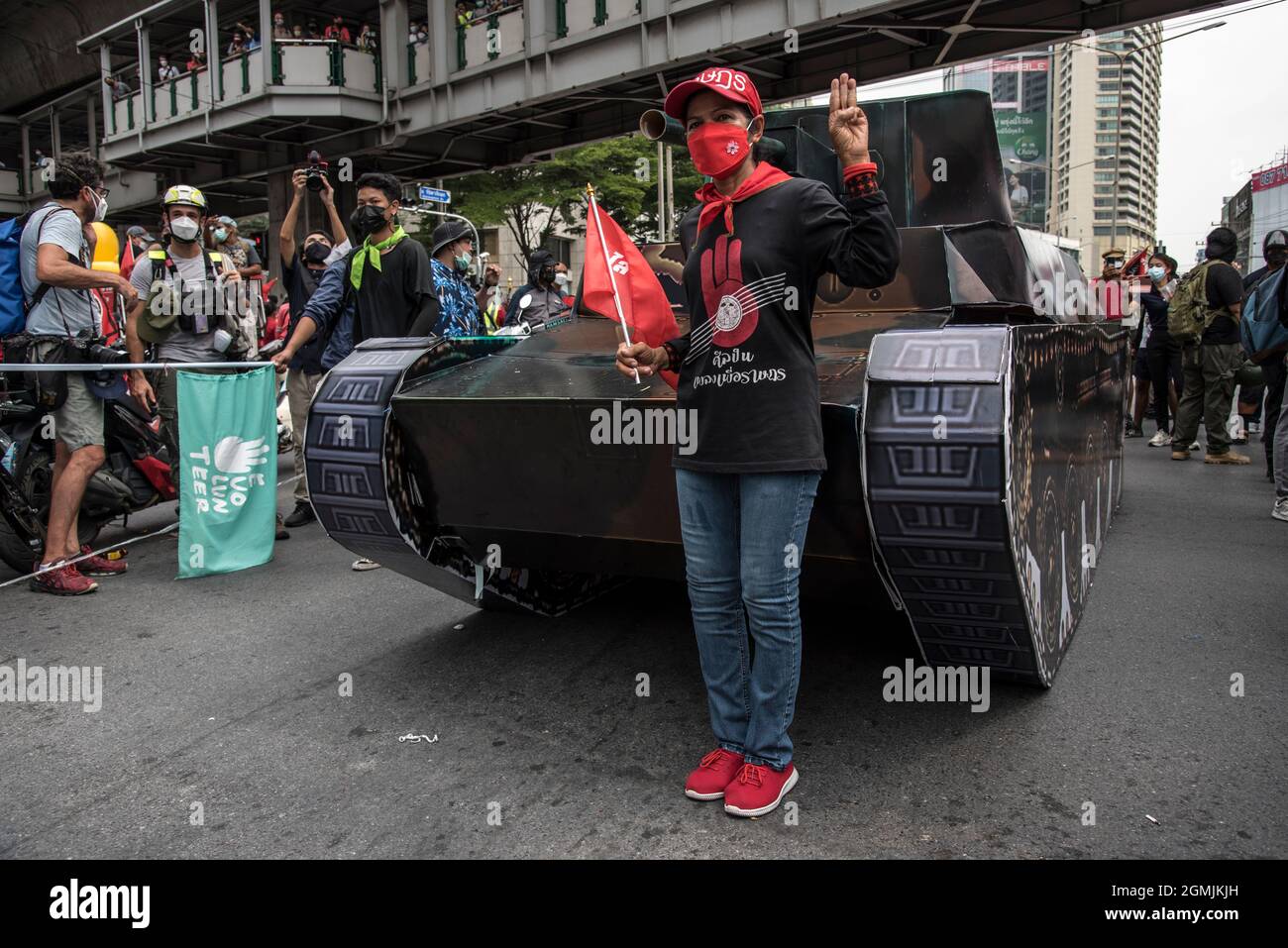 A protester makes a three-finger salute while standing next to a mock ...