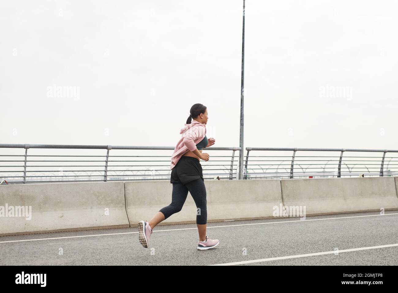 Rear view of young athlete running in the morning along the road on ...