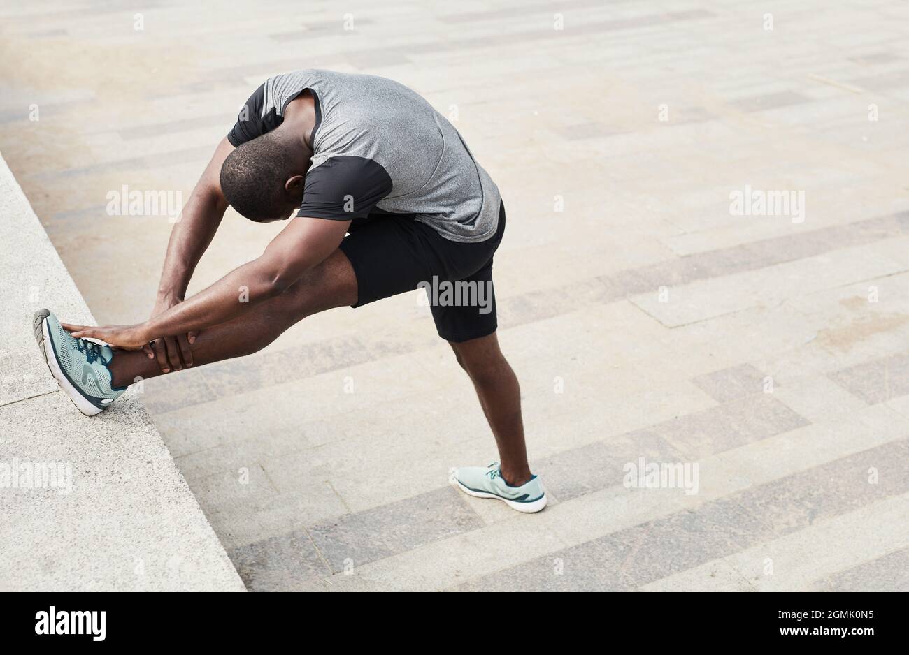 African young man doing stretching exercises during sports training ...