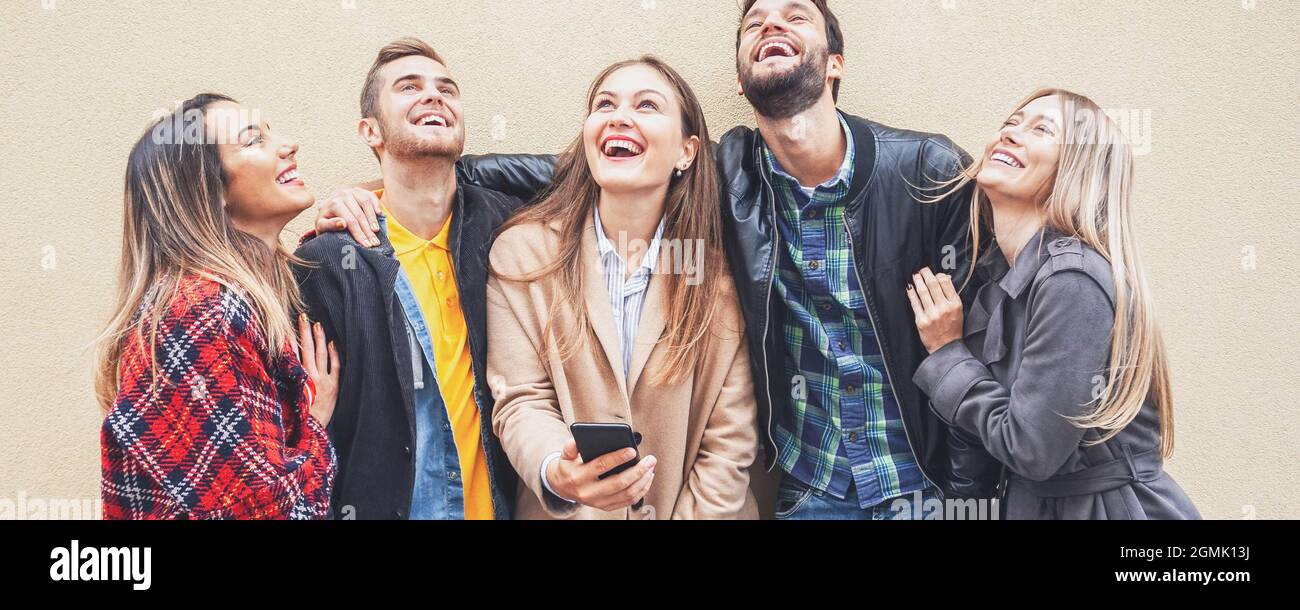 Group of friends standing by the wall background and enjoying each ...