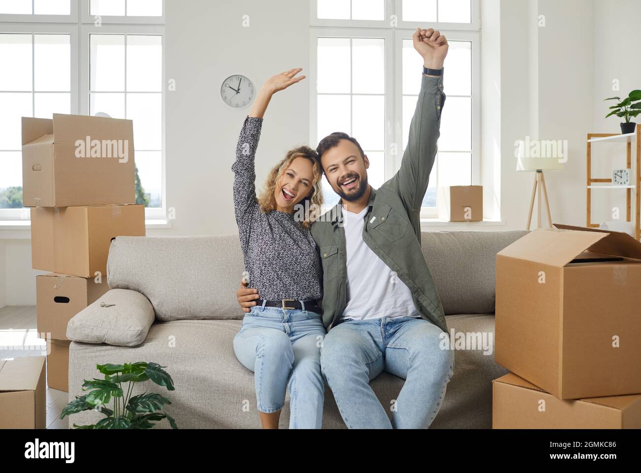 Happy excited young couple having fun sitting on couch in their new ...