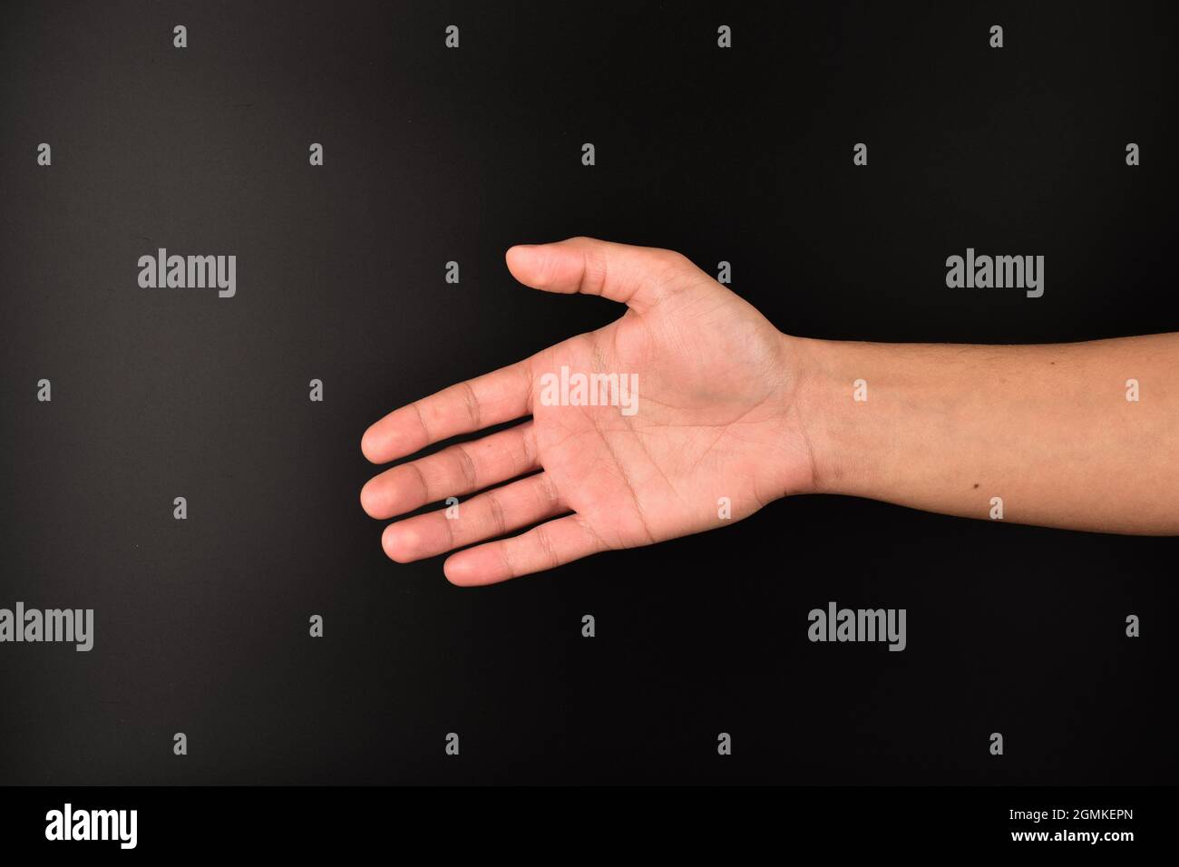 single hand offering handshake on dark background Stock Photo - Alamy