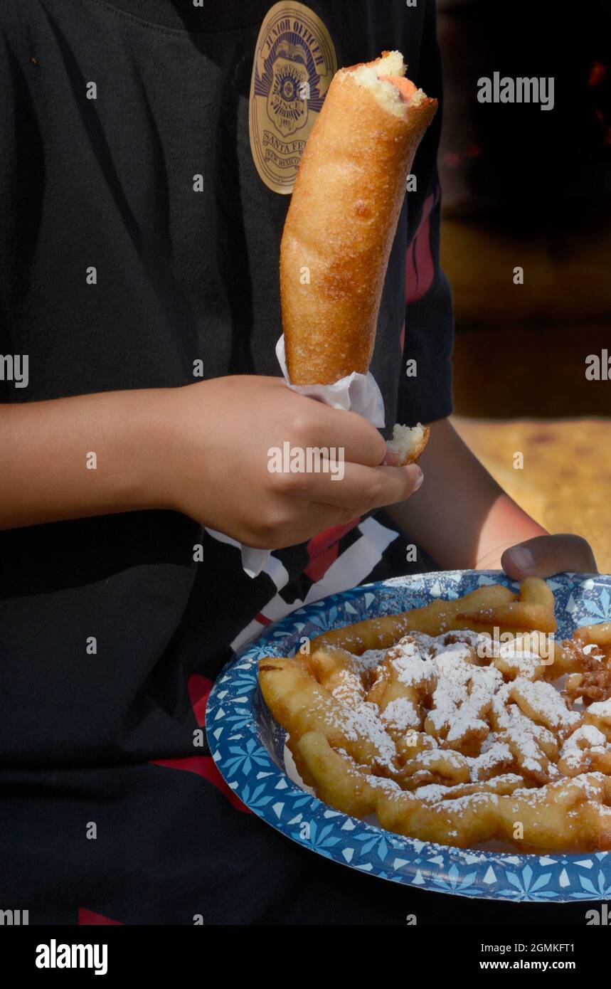A boy attempts to eat a funnel cake and hotdog on a stick purchased ...